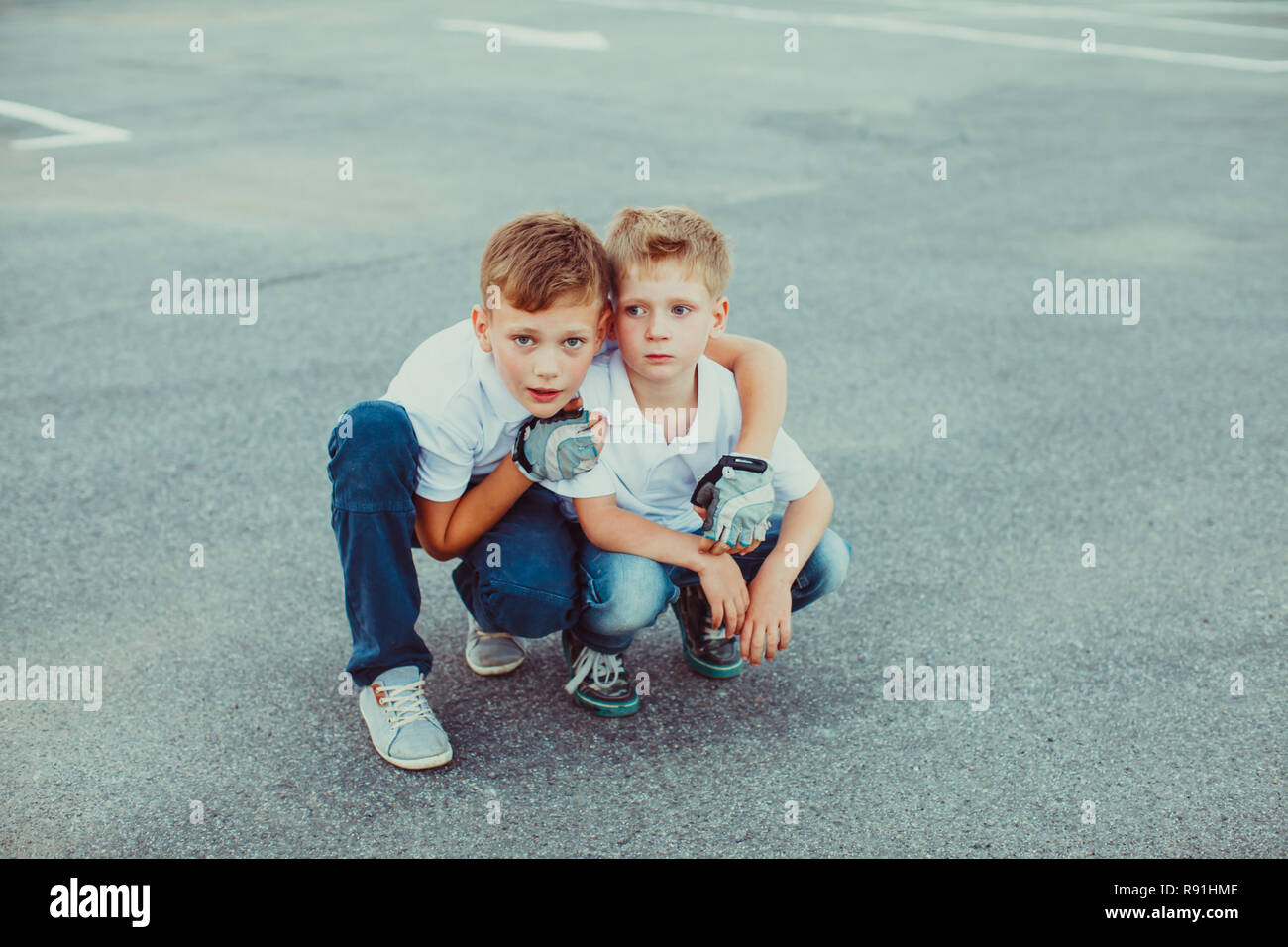 Two happy cute boys crouching on a ground Stock Photo - Alamy