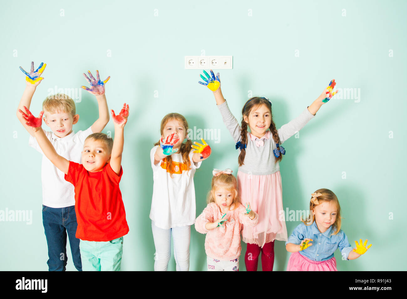 Happy kids holding their colored hands up Stock Photo - Alamy