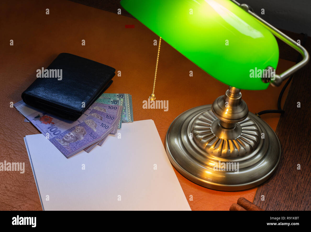 Malaysian money, Ringgit, on a stylish desk lit with a banking lamp ...