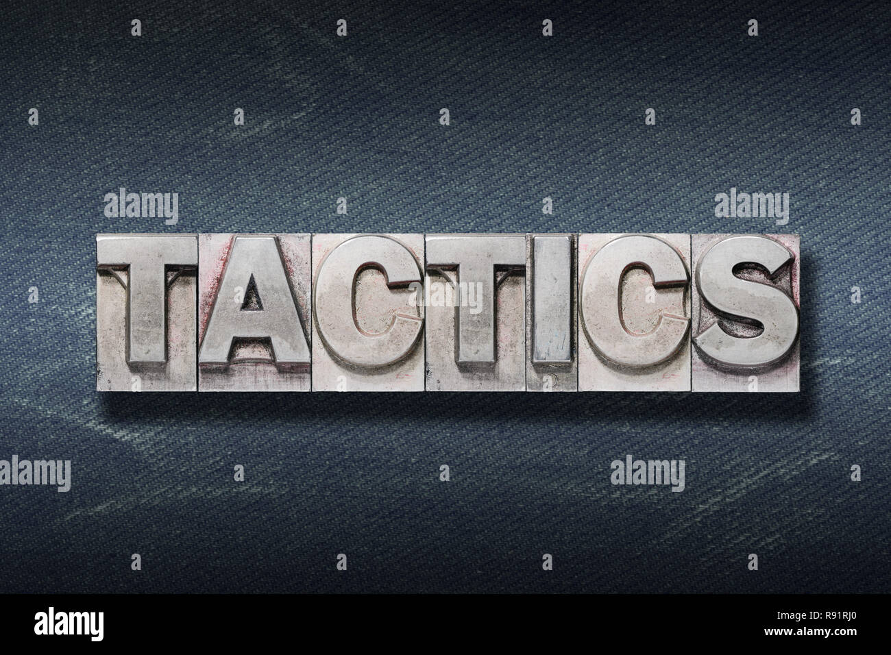 tactics word made from metallic letterpress on dark jeans background ...
