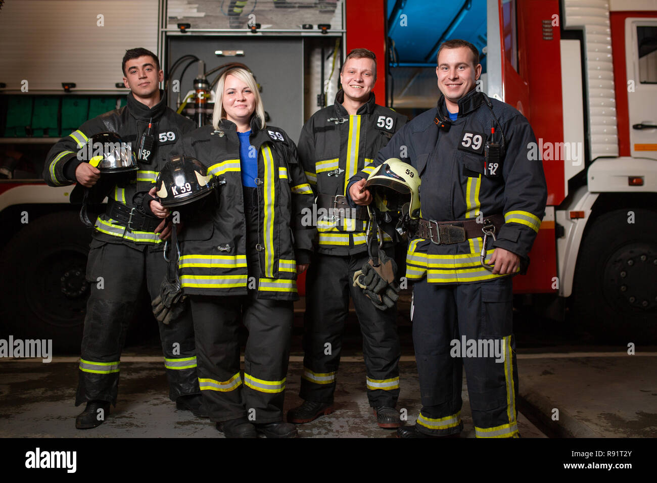 Full-length picture of three young fire men and woman on background of ...