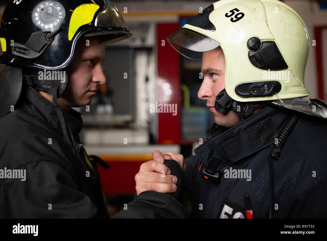 Photo of two firemen wearing helmets waving their handshake Stock Photo ...
