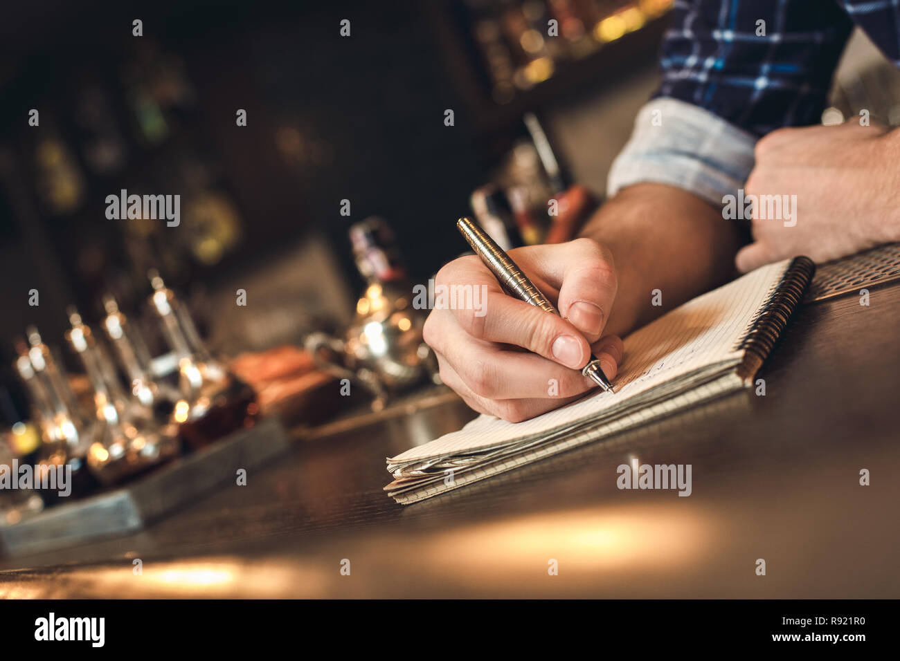 Young barman standing at bar counter taking notes to do list close-up ...