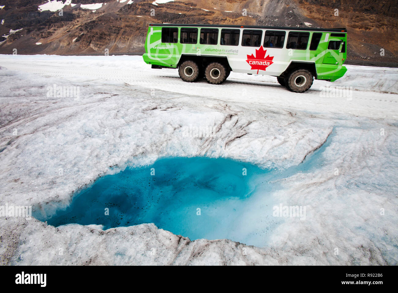 Meltwater pools and tourist buggy on the Athabasca glacier which is ...
