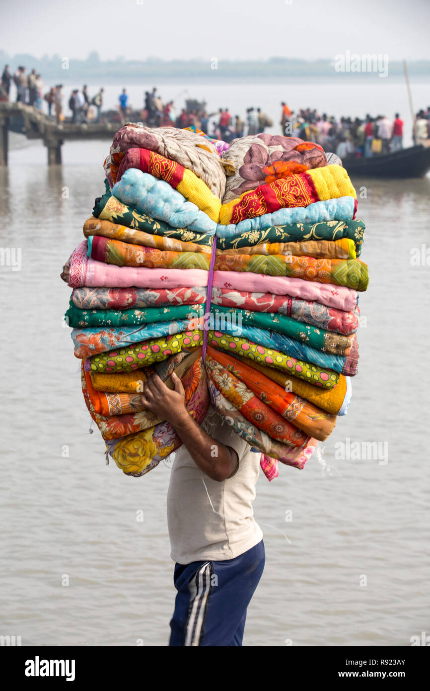Man carrying large stack of various fabrics in Ganges Delta, Sunderbans ...