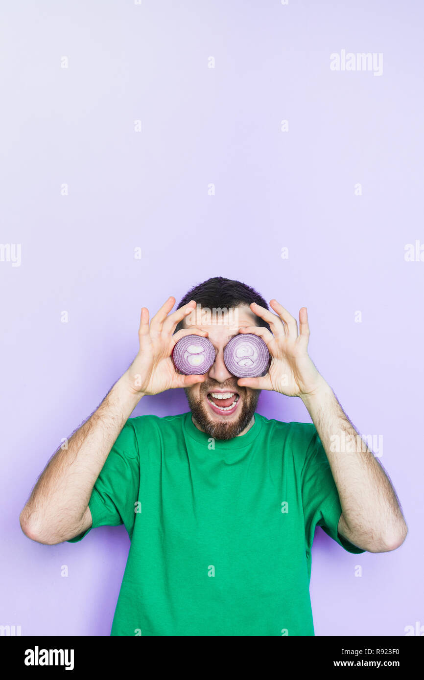 Young bearded holding slices of red onion in front of his eyes, mouth ...