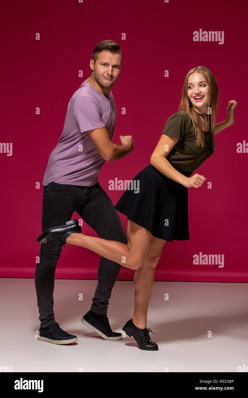 Funny young modern couple dancing and having fun together over burgundy ...