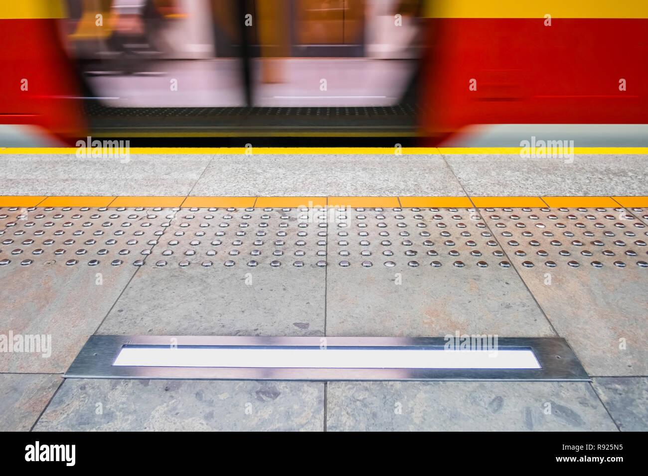 blurred red subway train, tactile paving also called detectable warning ...