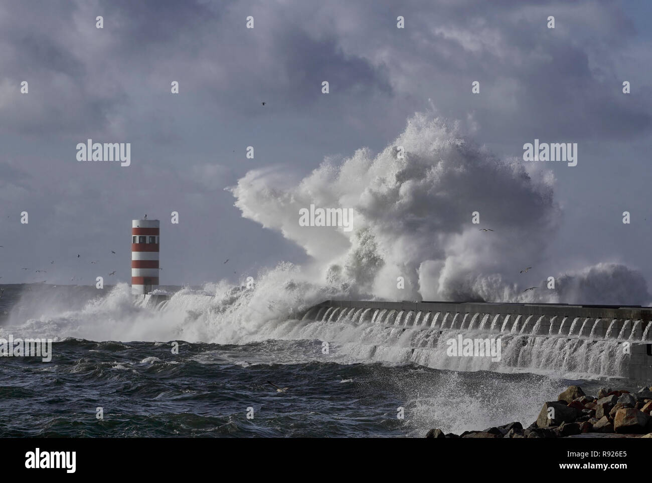 Huge stormy sea wave splash over pier and beacon closeup Stock Photo ...
