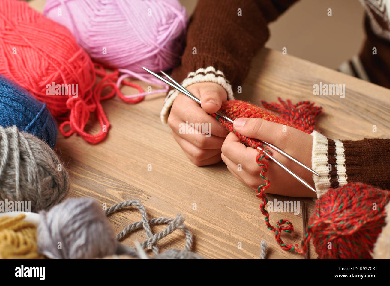 Child boy is learning to knit. Colorful wool yarns are on the wooden ...
