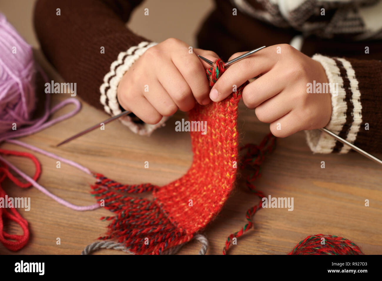 Child boy is learning to knit. Colorful wool yarns are on the wooden ...