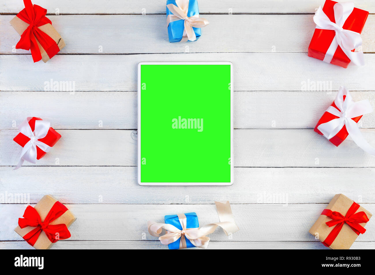 vertical tablet with green screen with holiday presents frame on wooden ...