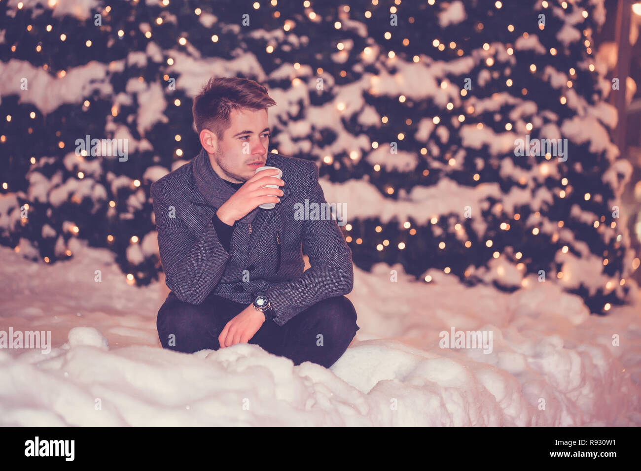 Night scene portrait of yung man while drinking mulled wine with winter ...