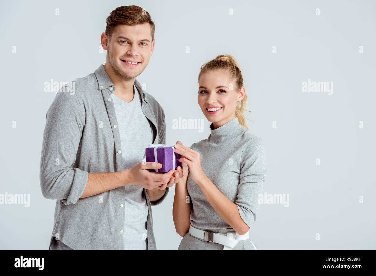 couple looking at camera and man giving present to woman isolated on ...