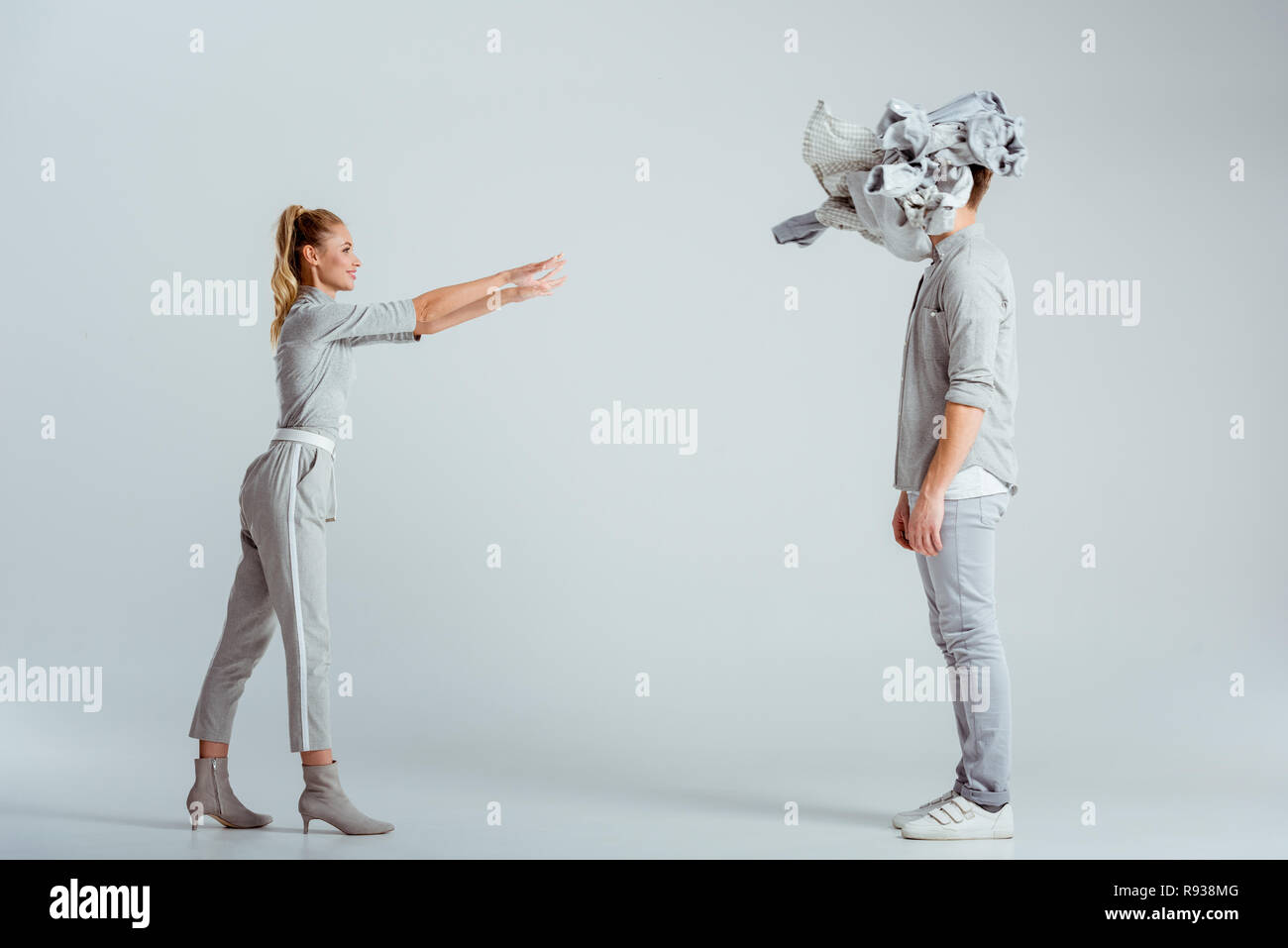 blonde woman throwing pile of clothes at man on grey background Stock ...