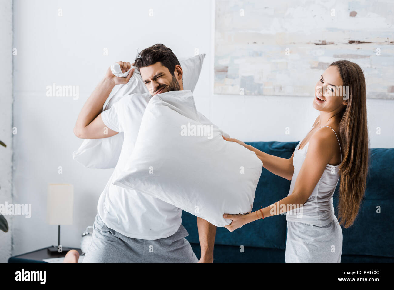 attractive emotional woman hitting boyfriend with pillow Stock Photo ...