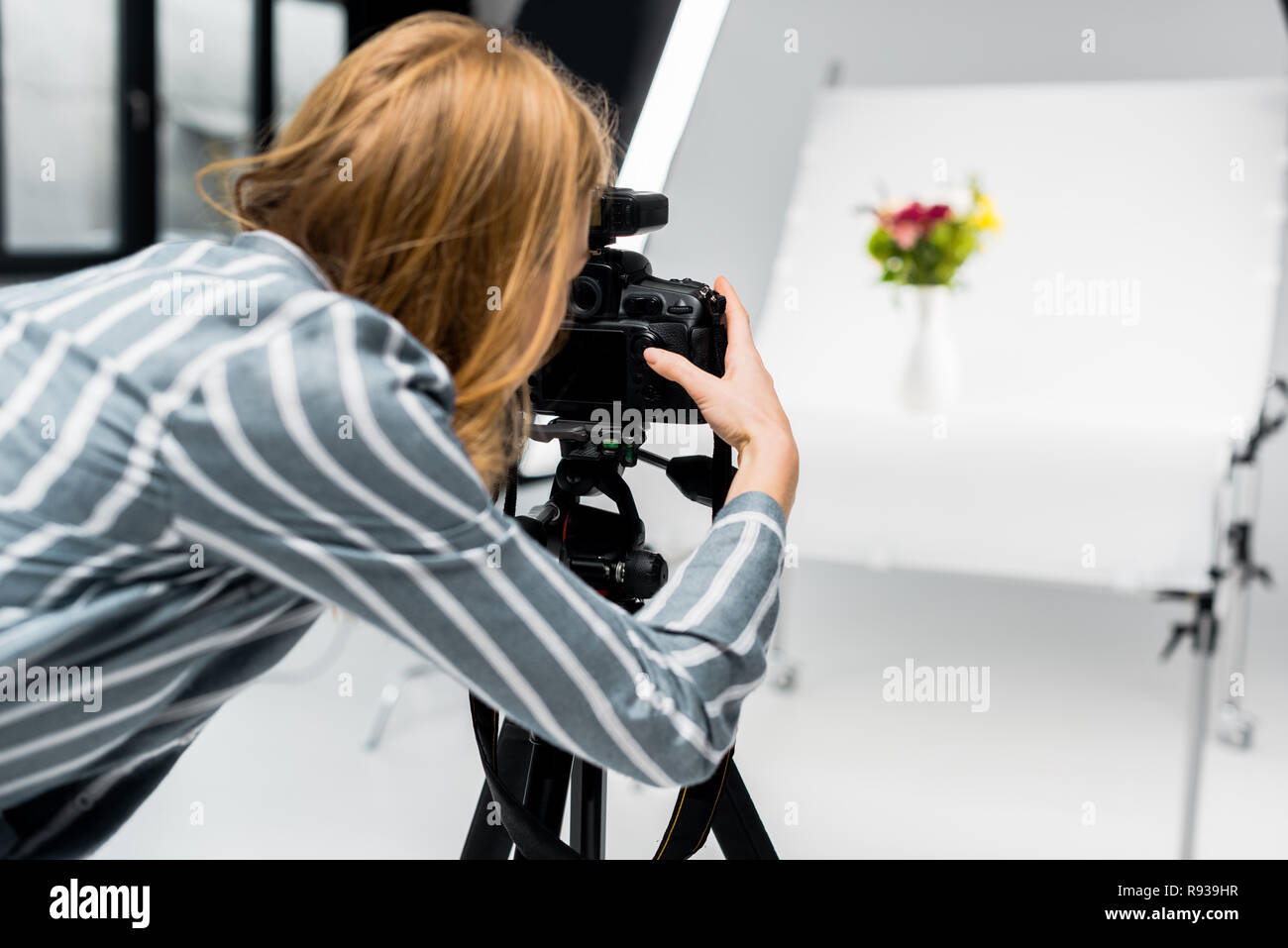 young woman shooting beautiful flowers in professional photo studio ...