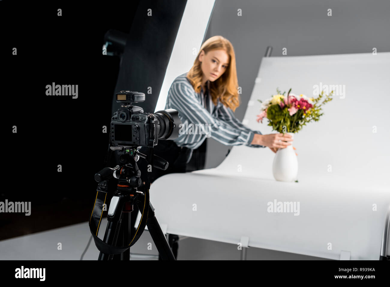 close-up view of photo camera and female photographer arranging flowers ...