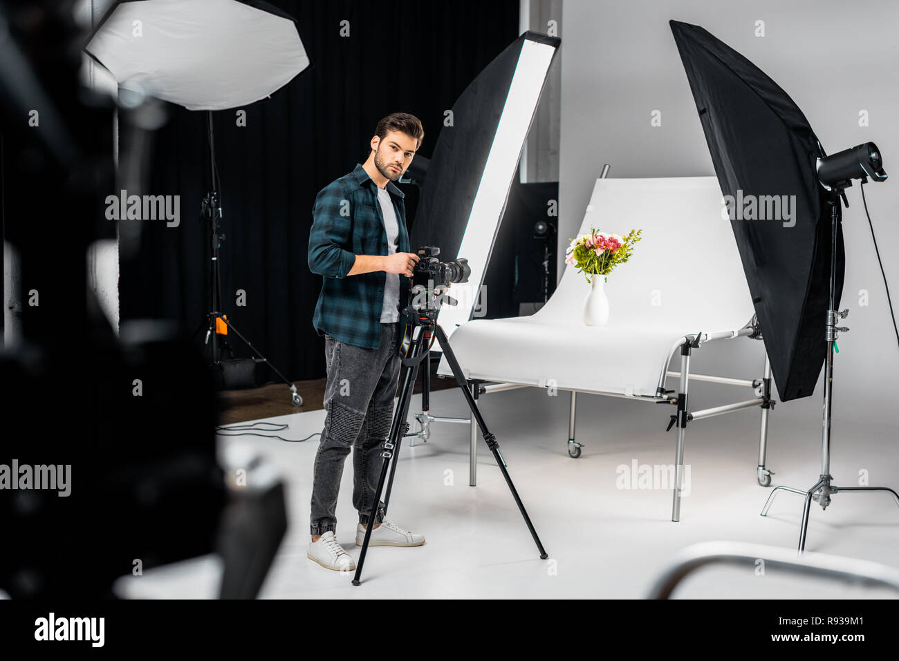handsome young photographer working with camera and lighting equipment ...