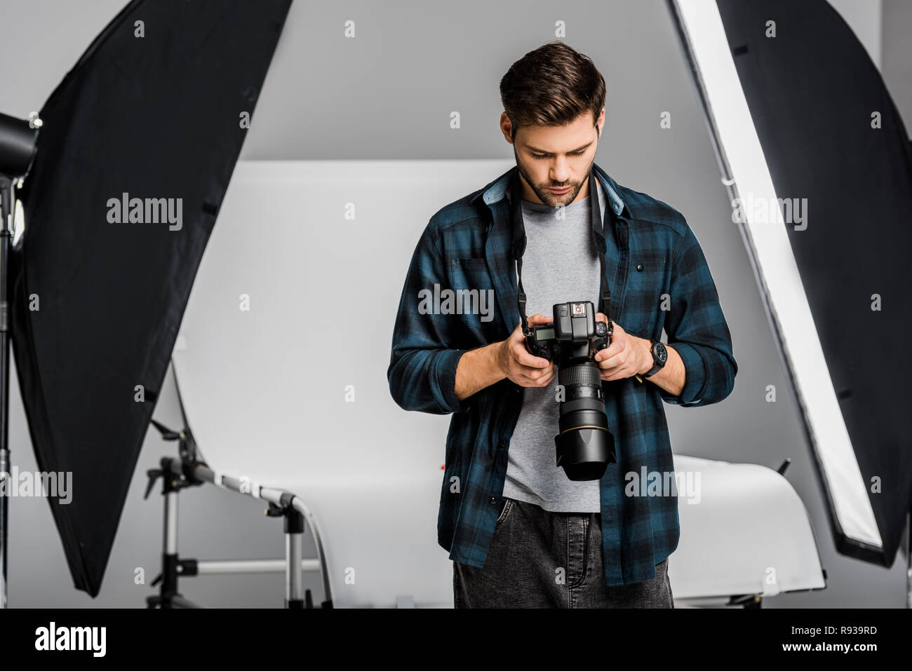 handsome professional young photographer using photo camera in studio ...