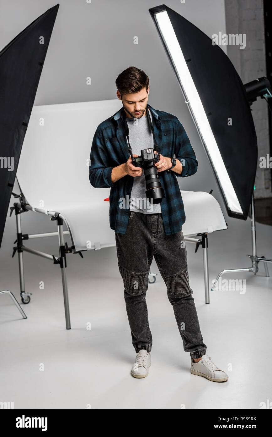 full length view of handsome professional young photographer using ...