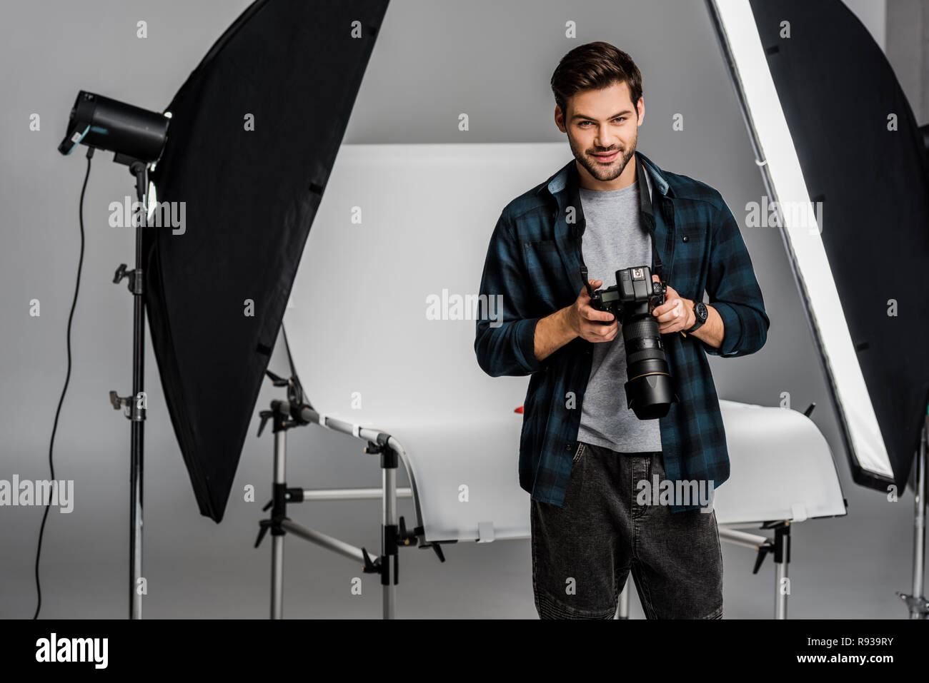 handsome professional young photographer smiling at camera while ...