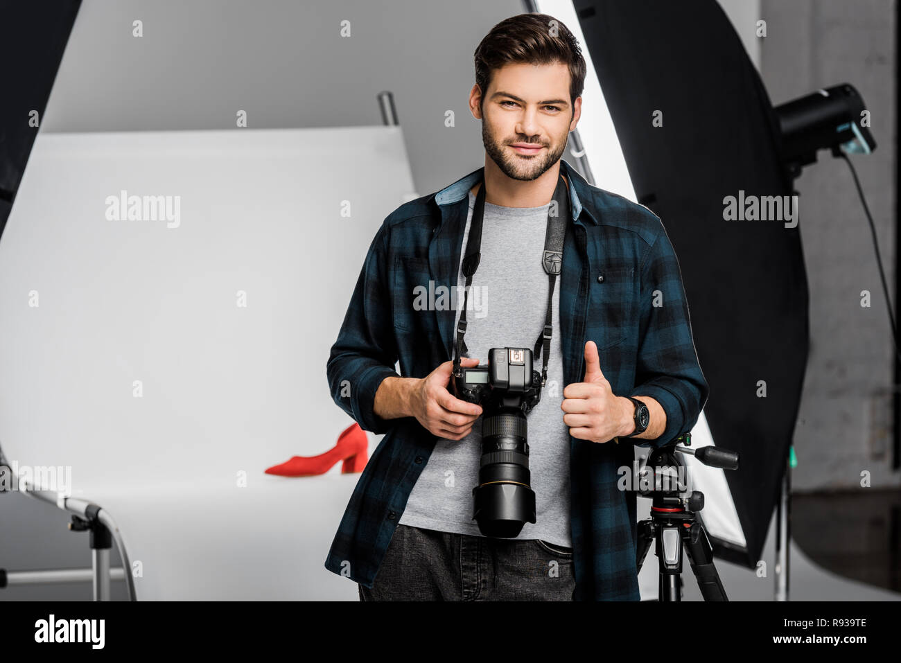 handsome smiling young photographer holding camera and showing thumb up ...