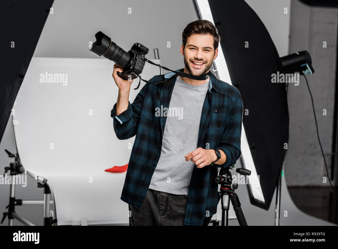 happy handsome young photographer holding professional photo camera in ...