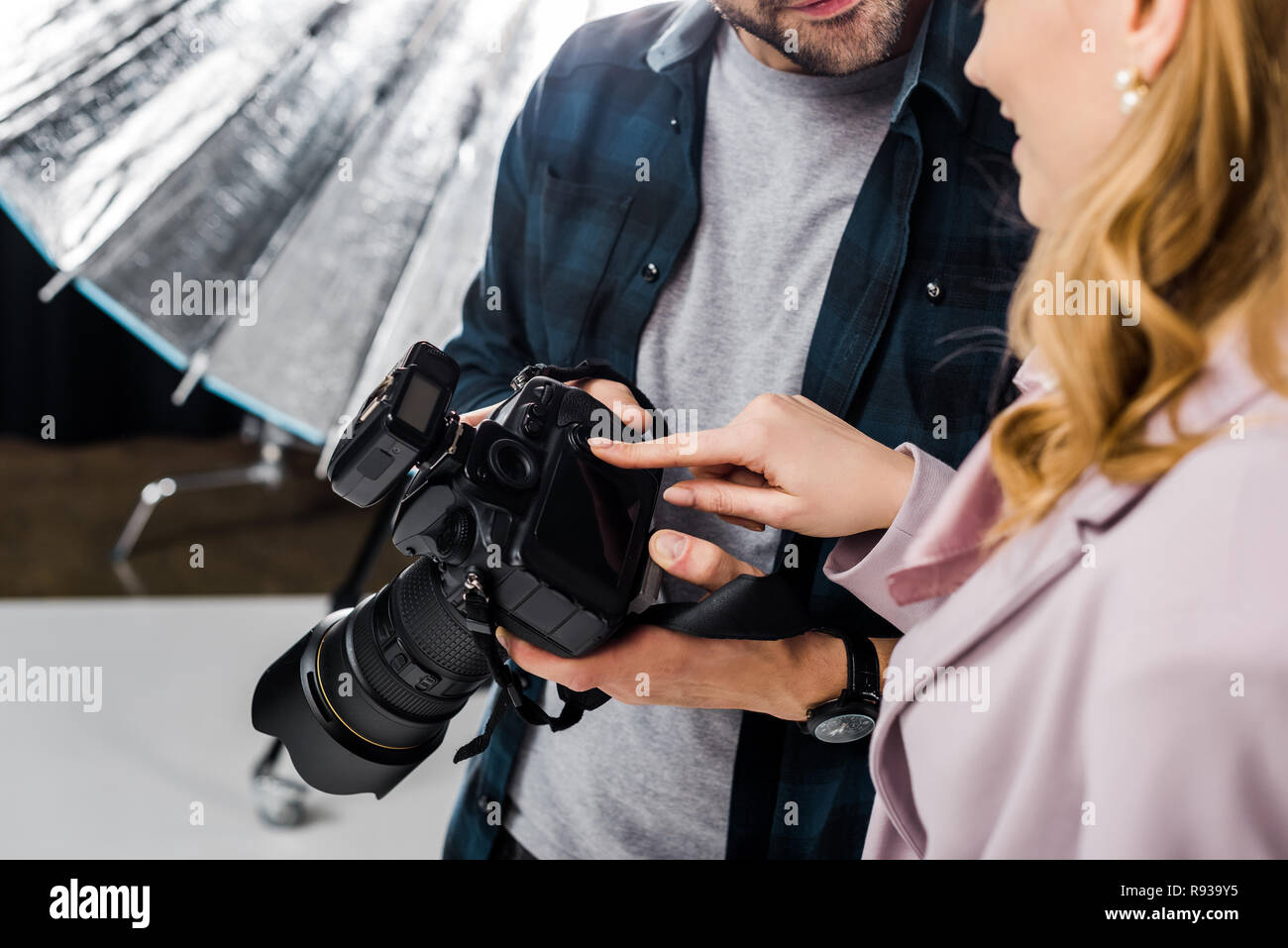 cropped shot of photographer and model using photo camera together ...