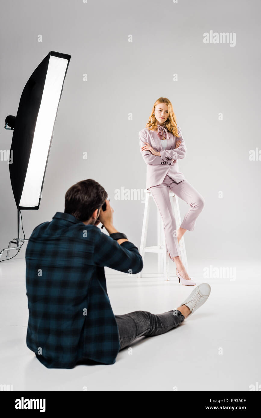 back view of photographer sitting and photographing beautiful female ...