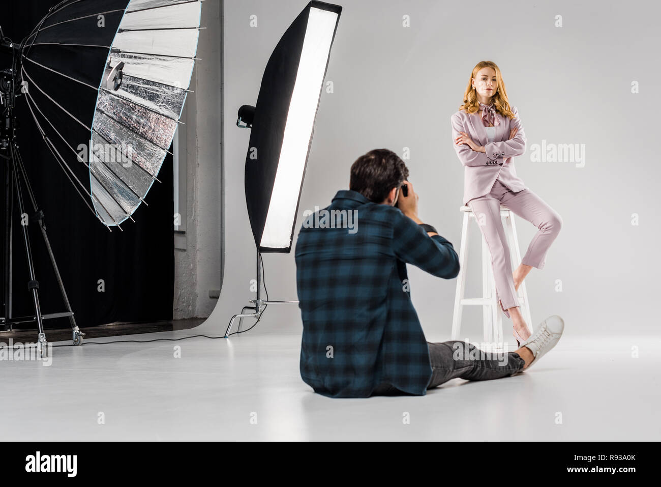 back view of photographer sitting and shooting beautiful female model ...