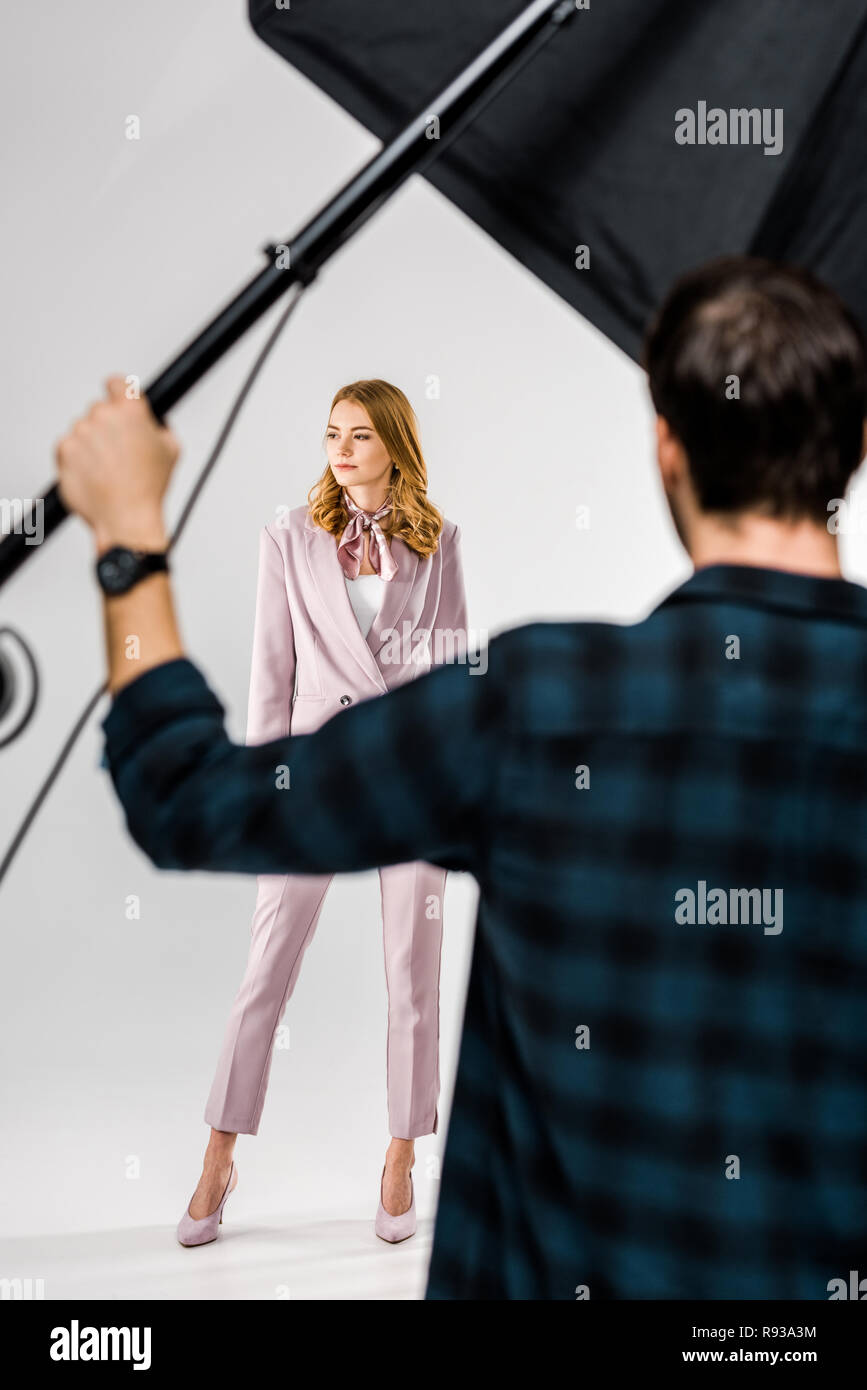 back view of photographer working with lighting equipment while female ...