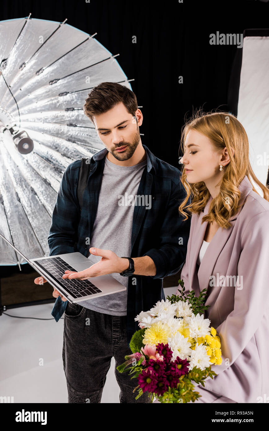 young photographer showing laptop to beautiful female model in photo ...