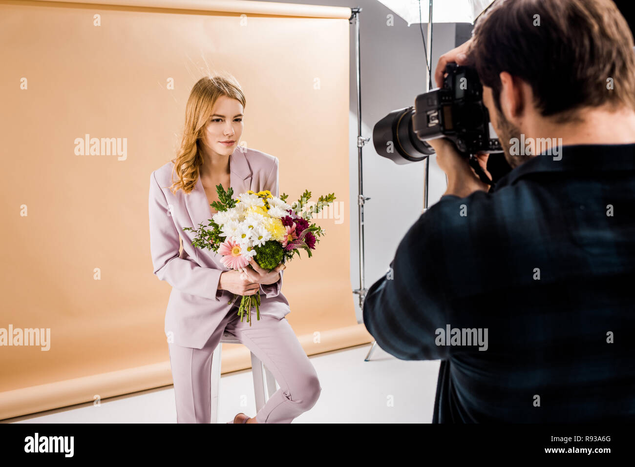 photographer shooting beautiful young woman posing with flowers in ...