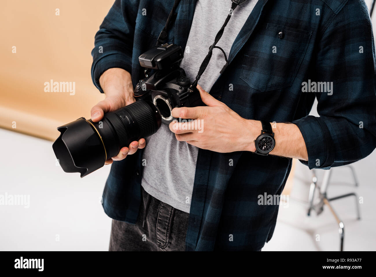 mid section of young photographer holding professional photo camera in ...