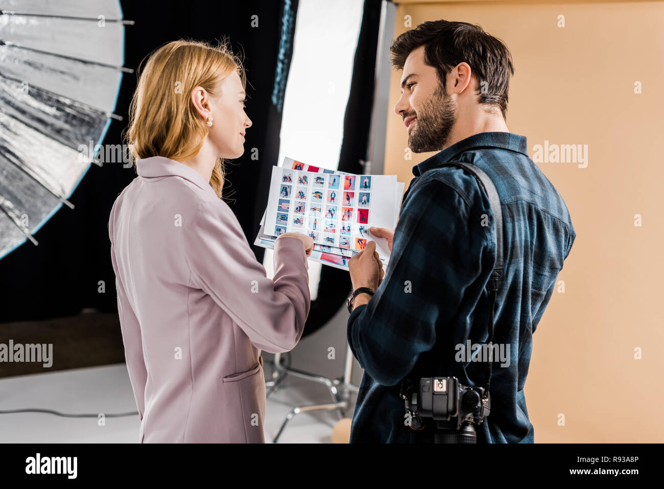 back view of young photographer and model holding photos and smiling ...