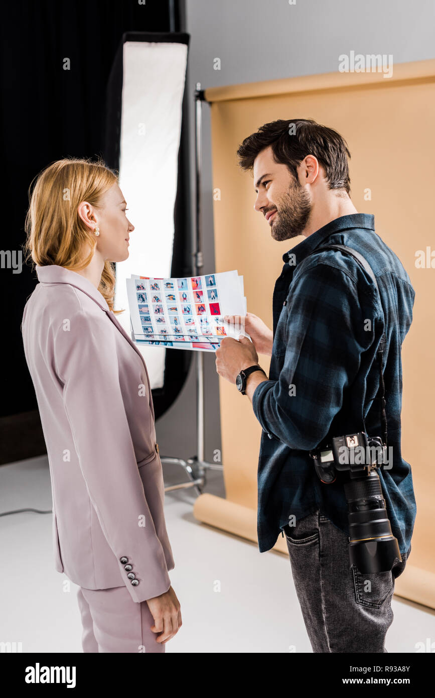 side view of young photographer and model discussing photos and smiling ...
