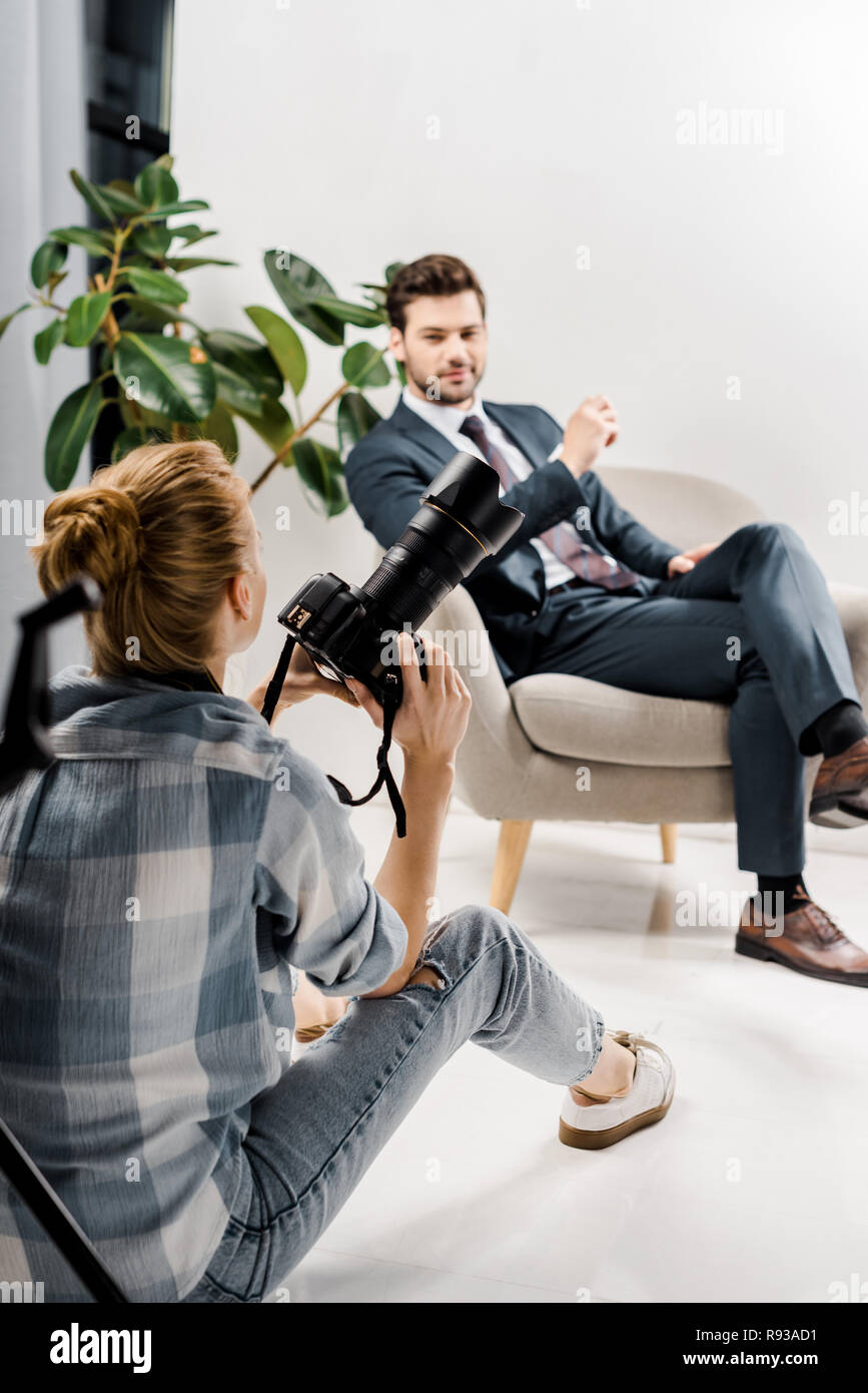 back view of female photographer with camera photographing handsome ...