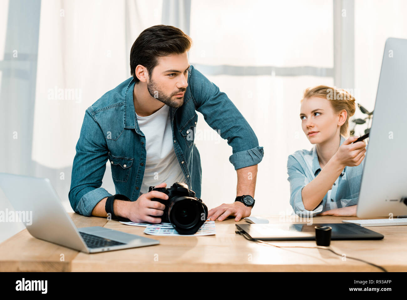 professional young photographers using desktop computers and discussing ...