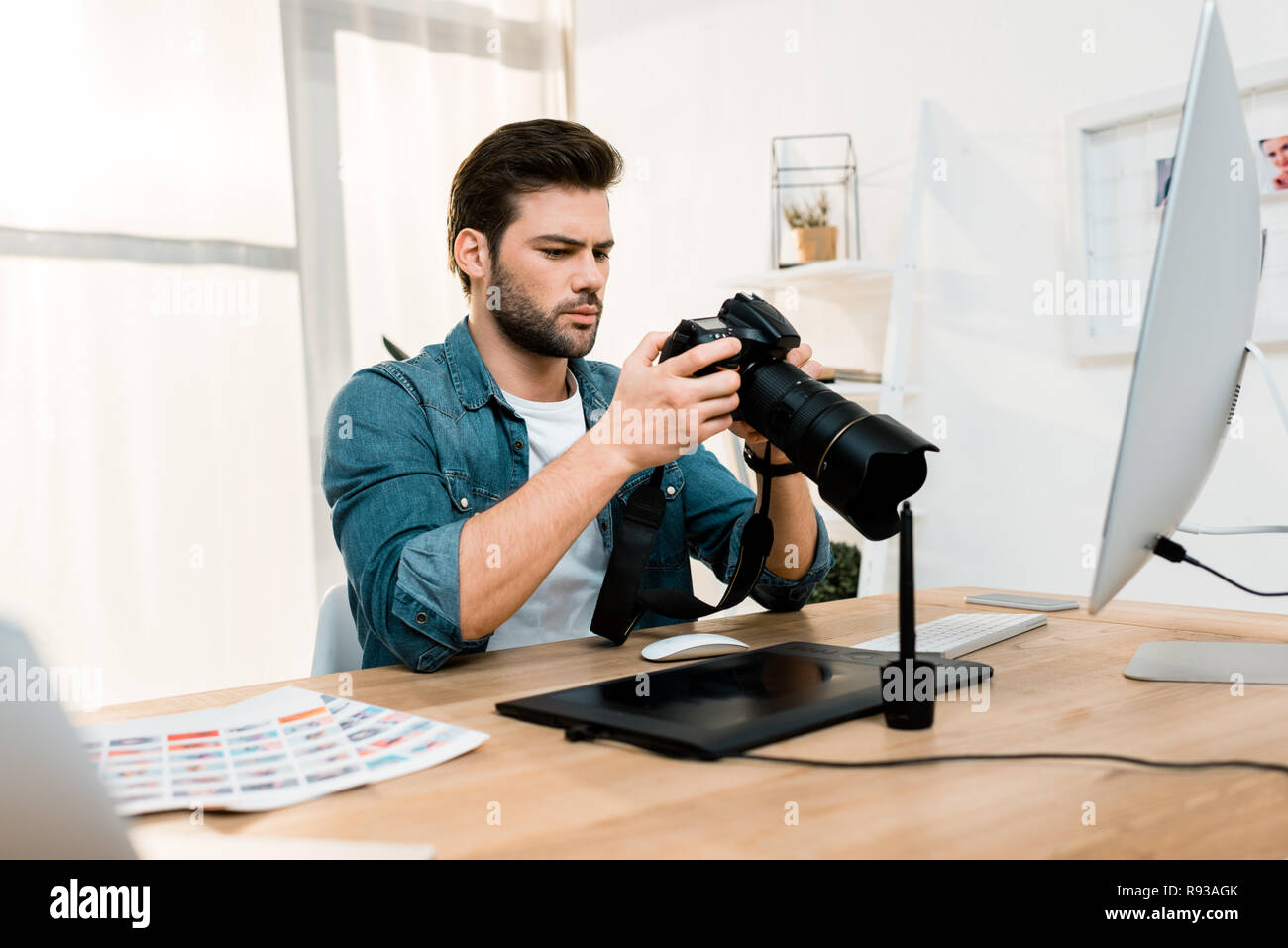 handsome professional young photographer using camera at workplace ...