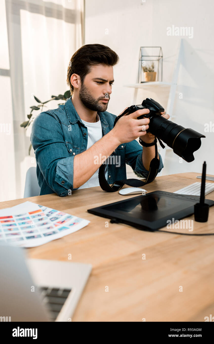 handsome young photographer using camera at workplace Stock Photo - Alamy