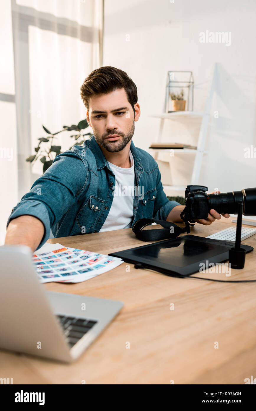 handsome young photographer using camera and laptop at workplace Stock ...