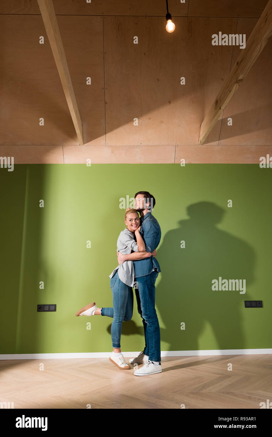 loving family couple hugging by green wall in apartment Stock Photo - Alamy