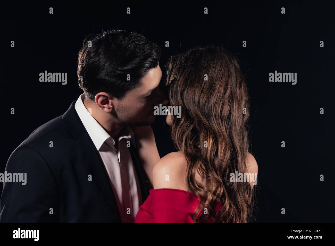 romantic couple in formal wear kissing isolated on black Stock Photo ...