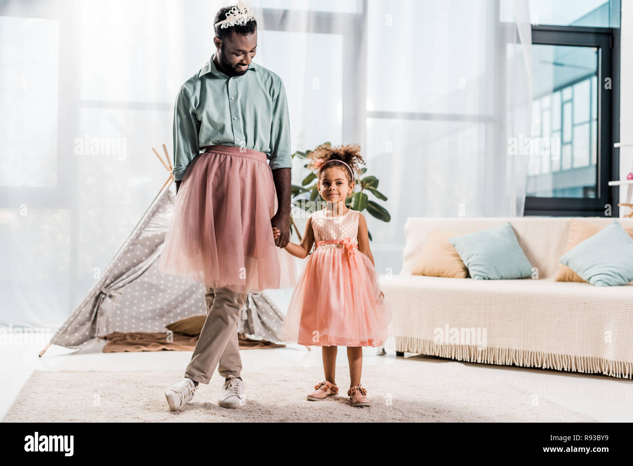 happy african american father and adorable daughter dancing in pink ...