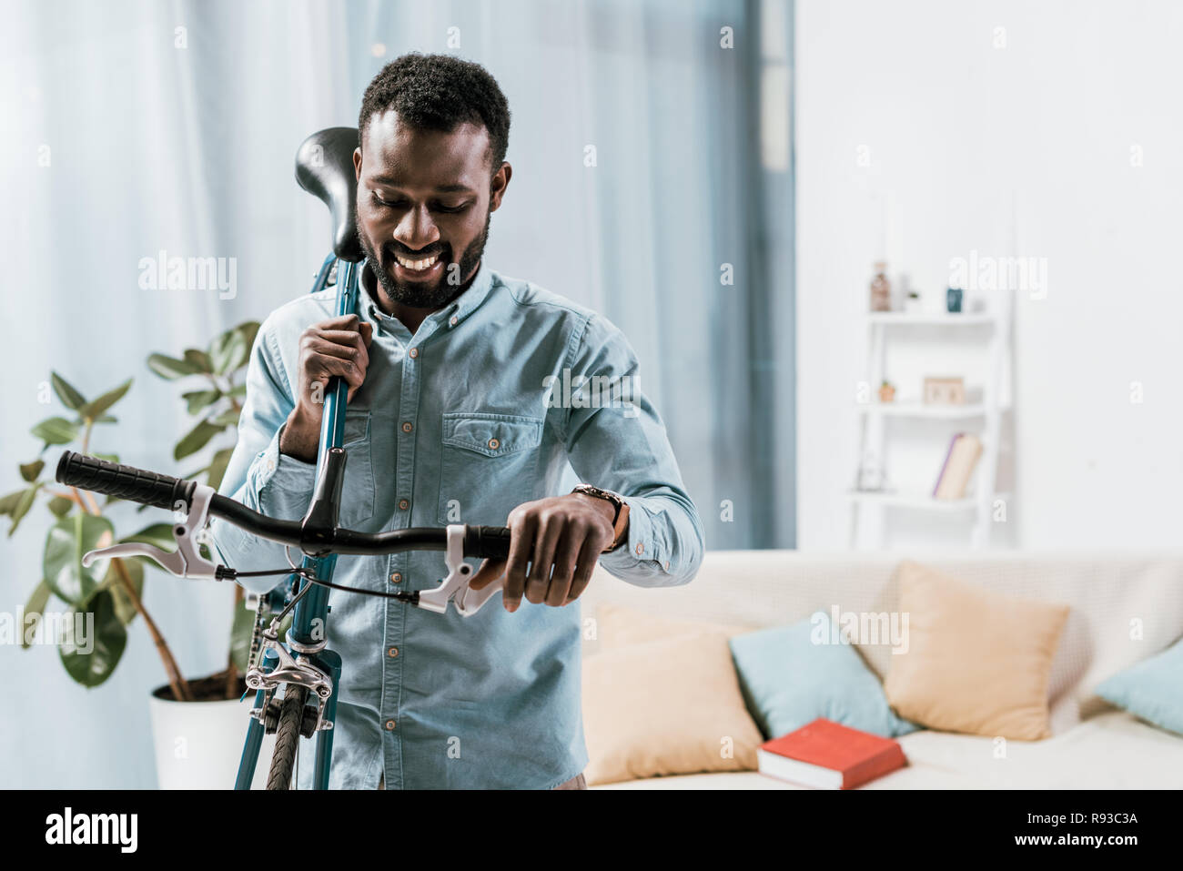 african american man carrying bike on shoulder in living room Stock ...