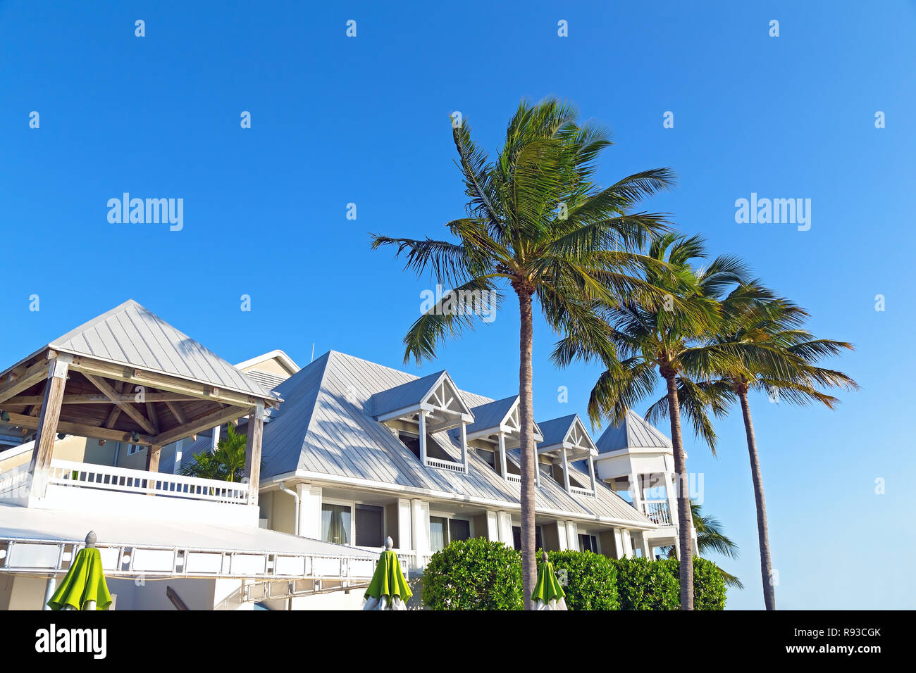 Resort building facing the evening sun. Palms, umbrellas and building ...