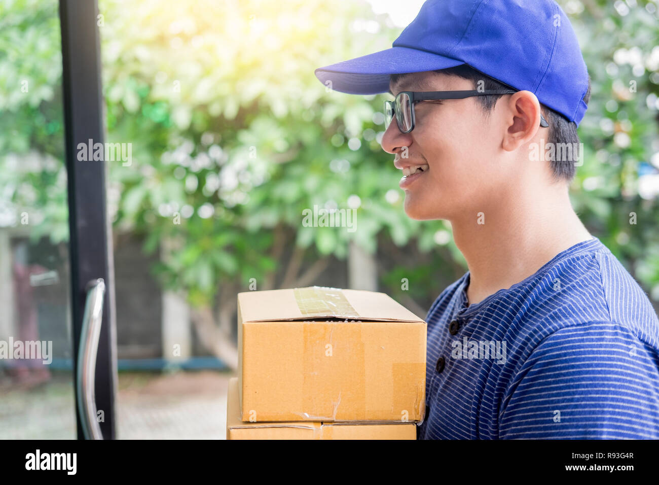 Delivery Loader Postman in blue uniform holding pile of cardboard box ...