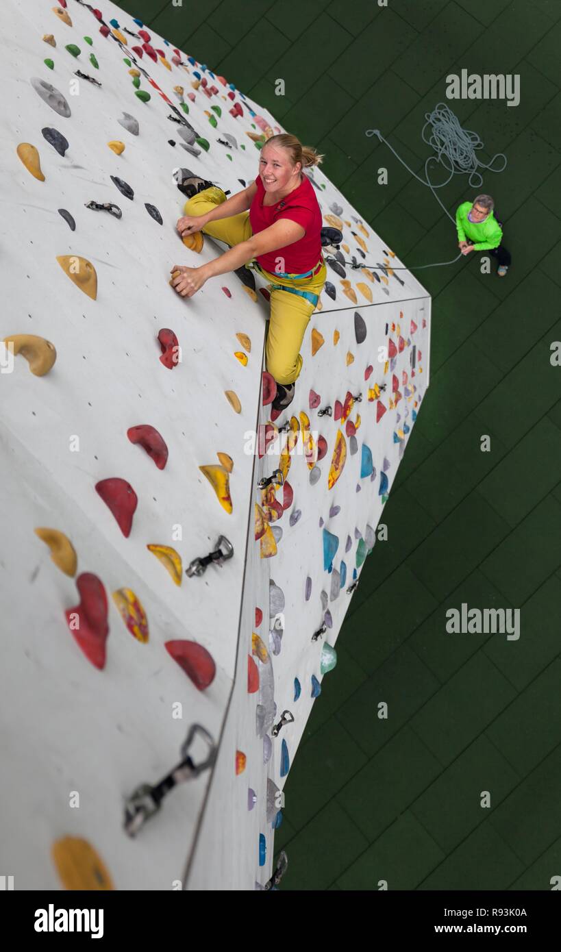 Climbing, woman climbs in front, at artificial climbing facility ...