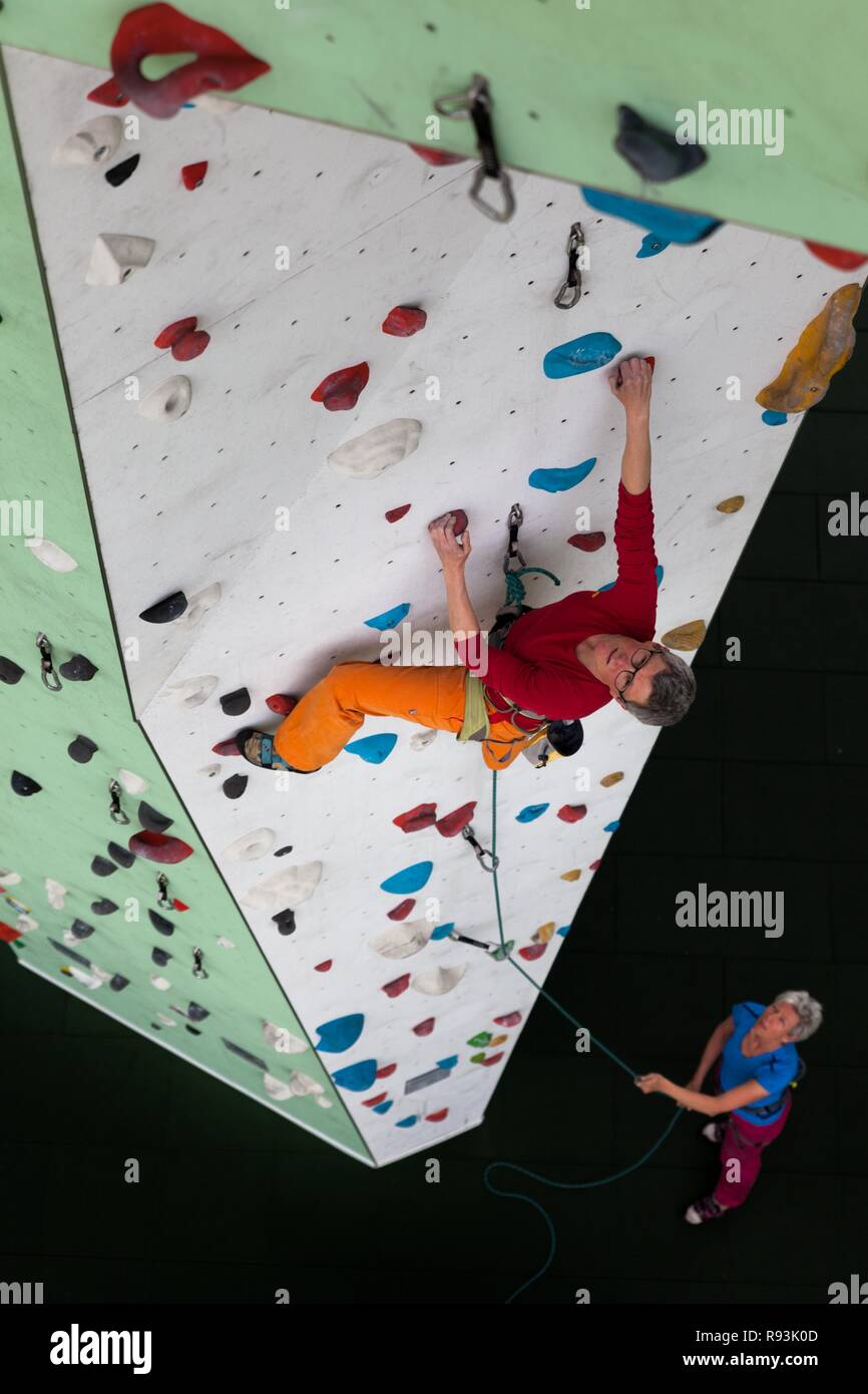 Climbing, woman climbs in front, at artificial climbing facility ...